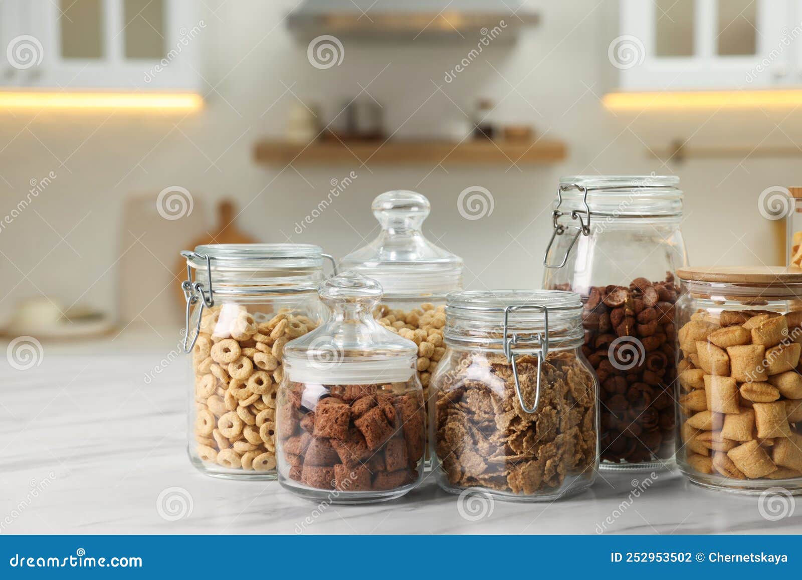 Glass Containers with Different Breakfast Cereals on White Marble Table ...