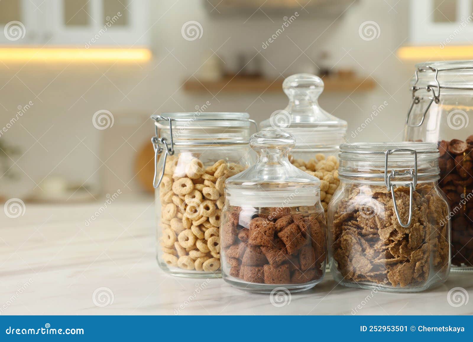 Glass Containers with Different Breakfast Cereals on White Marble Table ...