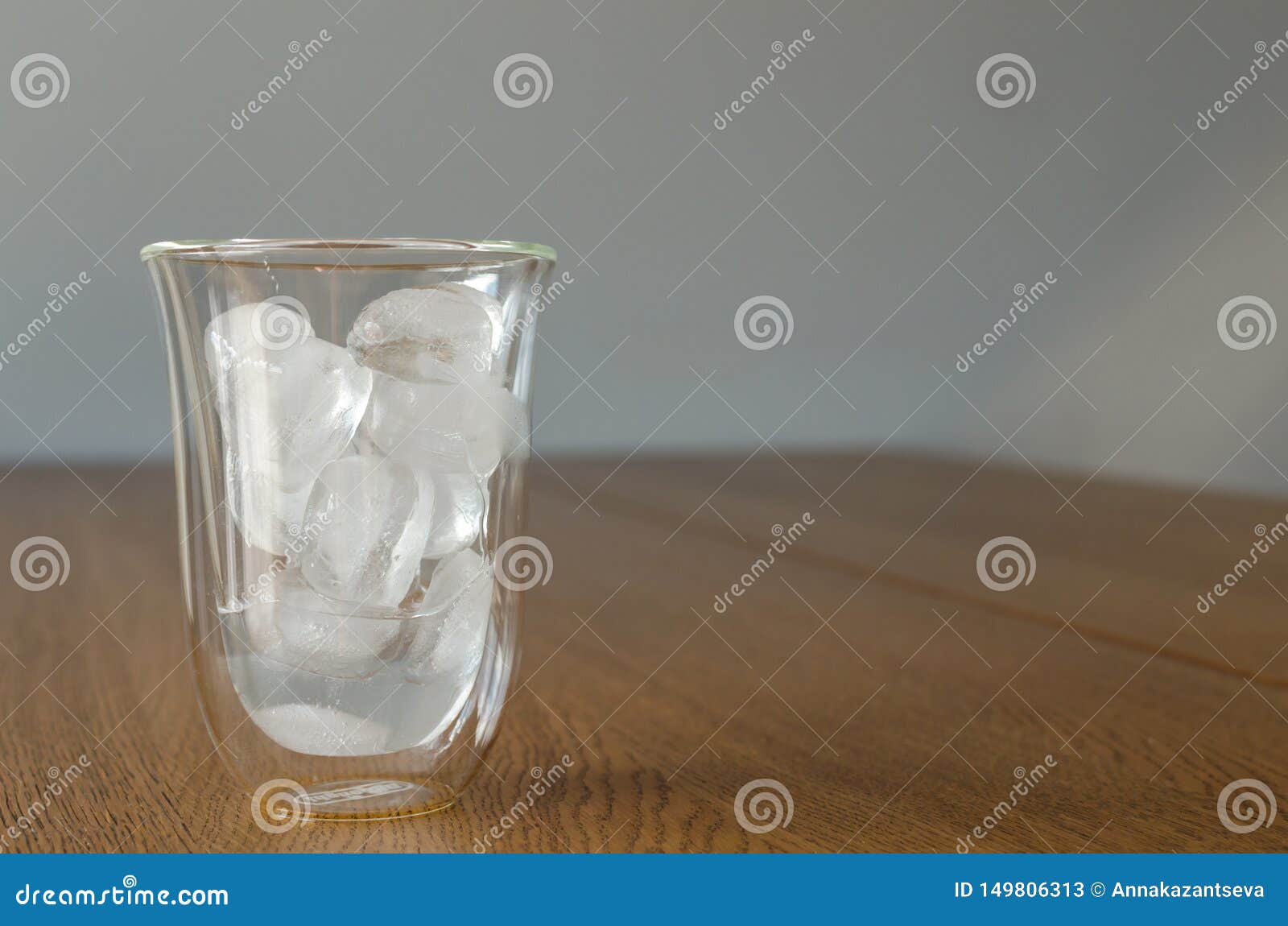 Glass with Half Melting Ice Pieces on the Wooden Table. Ice is ...