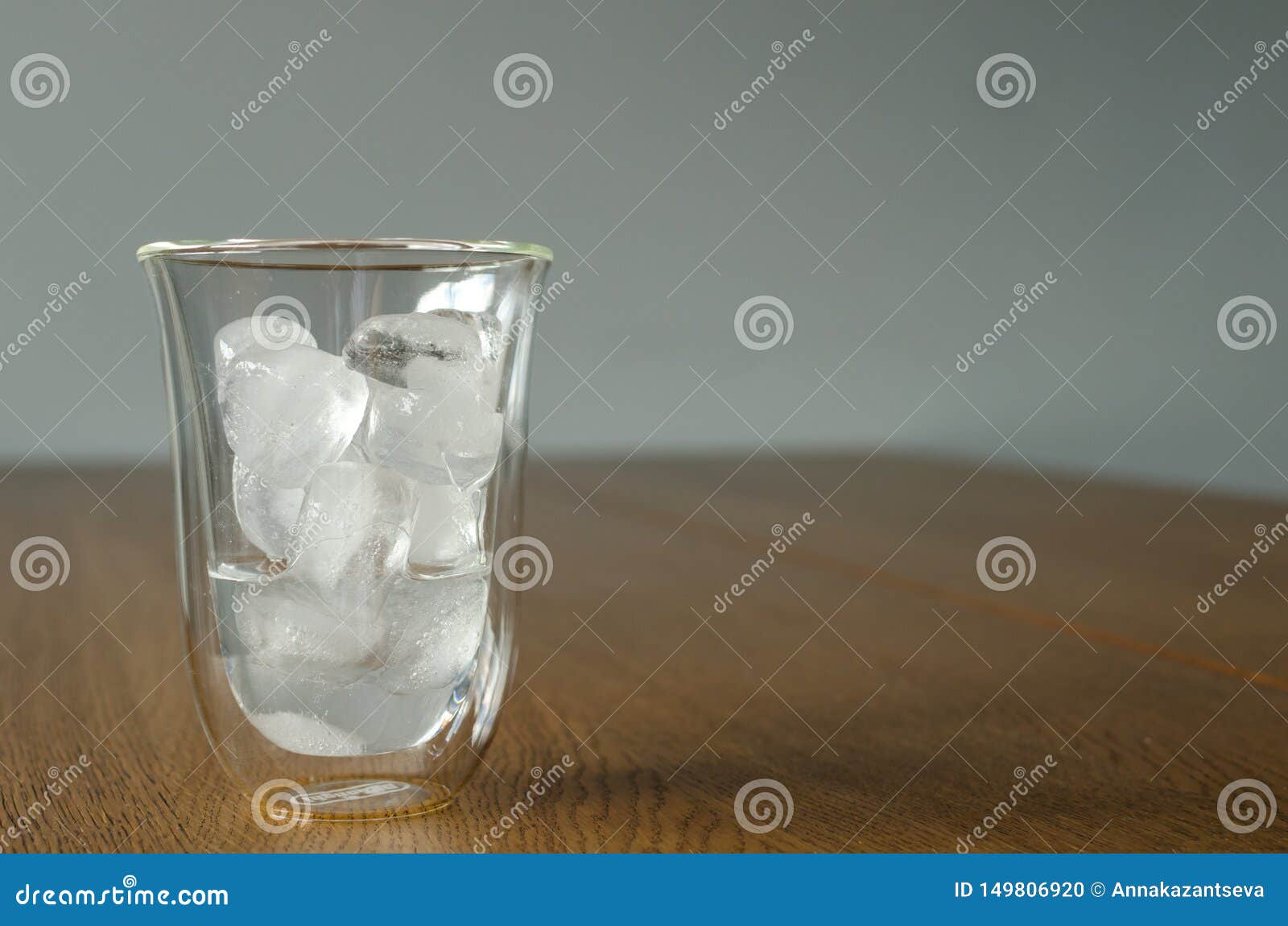 Glass with Half Melting Ice Pieces on the Wooden Table. Ice is ...