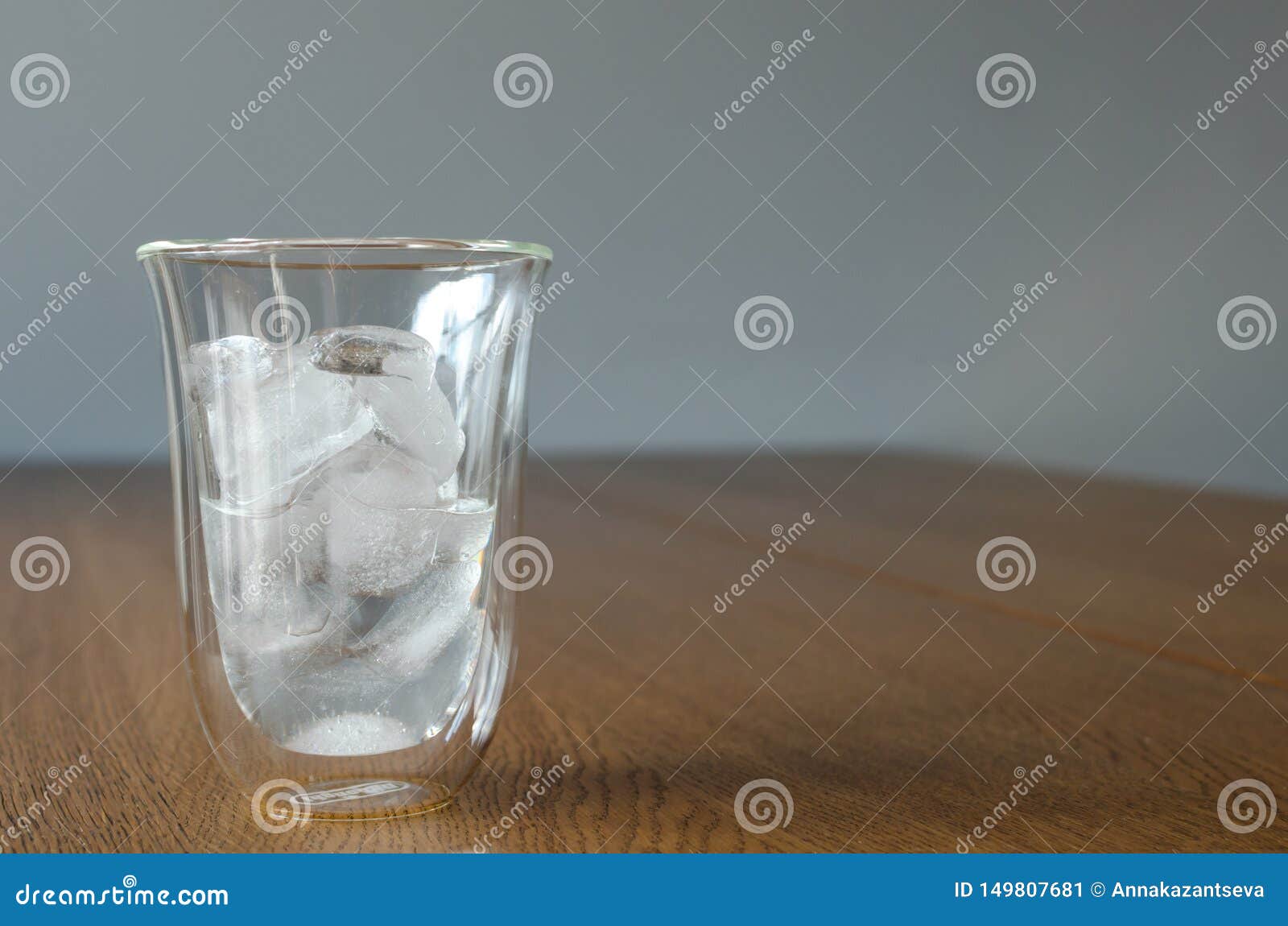 Glass with Half Melting Ice Pieces on the Wooden Table. Ice is ...