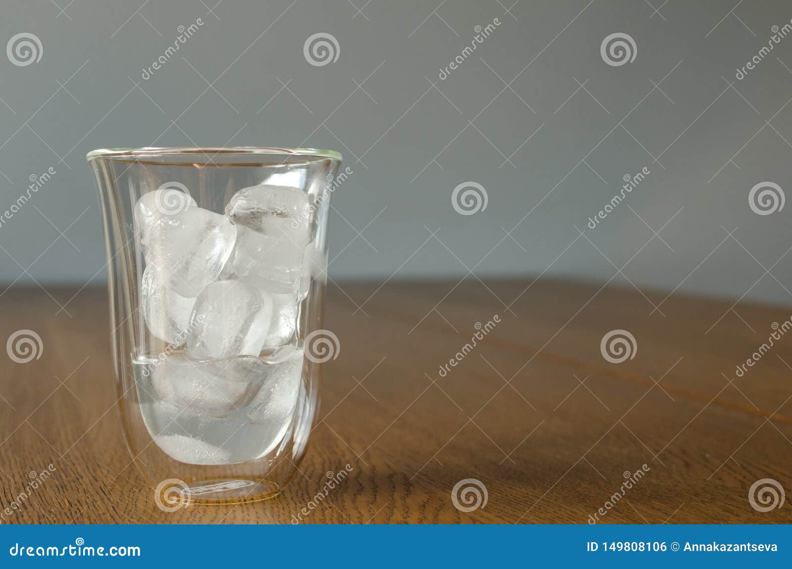 Glass with Half Melting Ice Pieces on the Wooden Table. Ice is ...