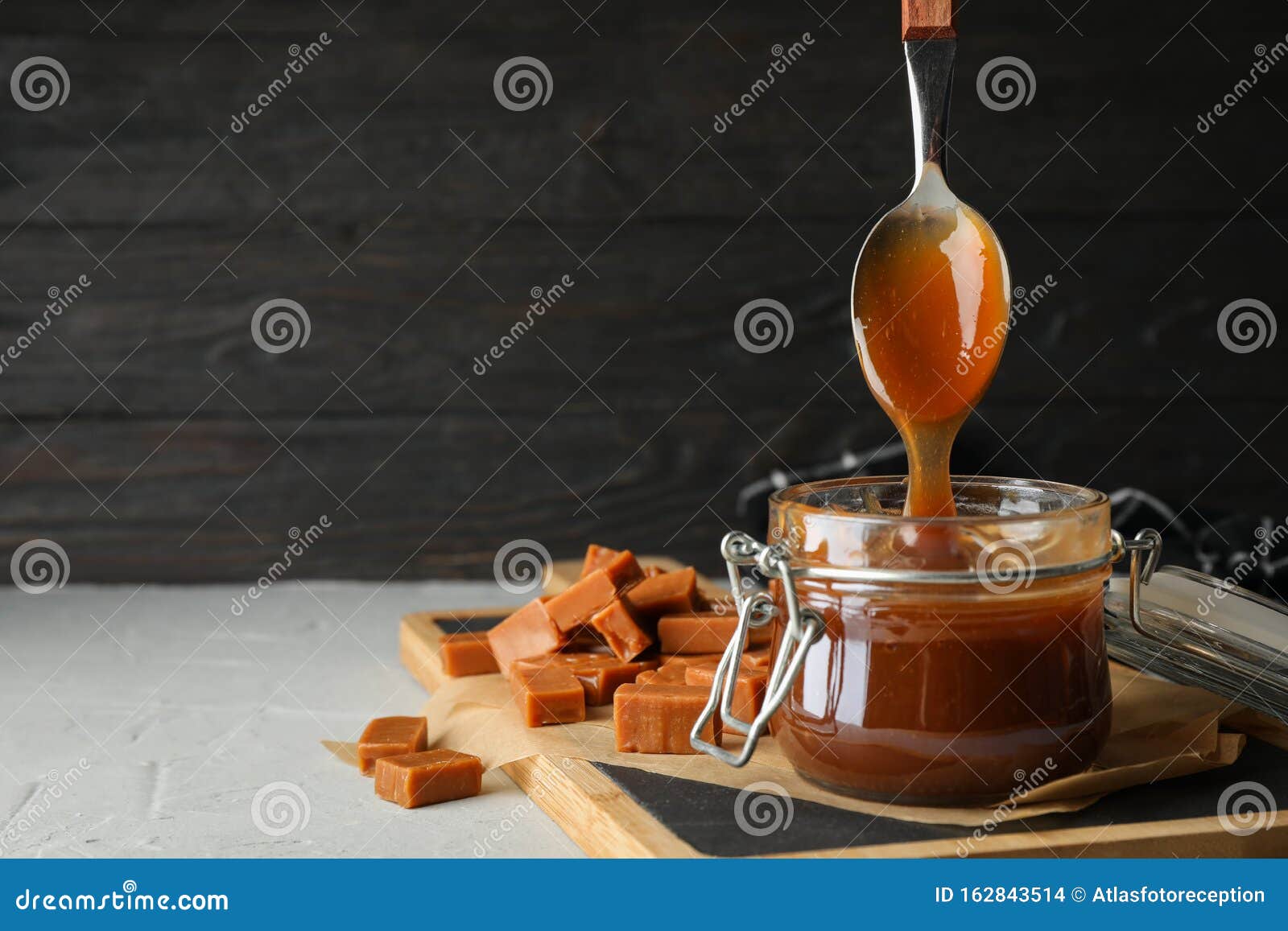 Glass Jar with Salted Caramel and Candies on Grey Background Stock ...