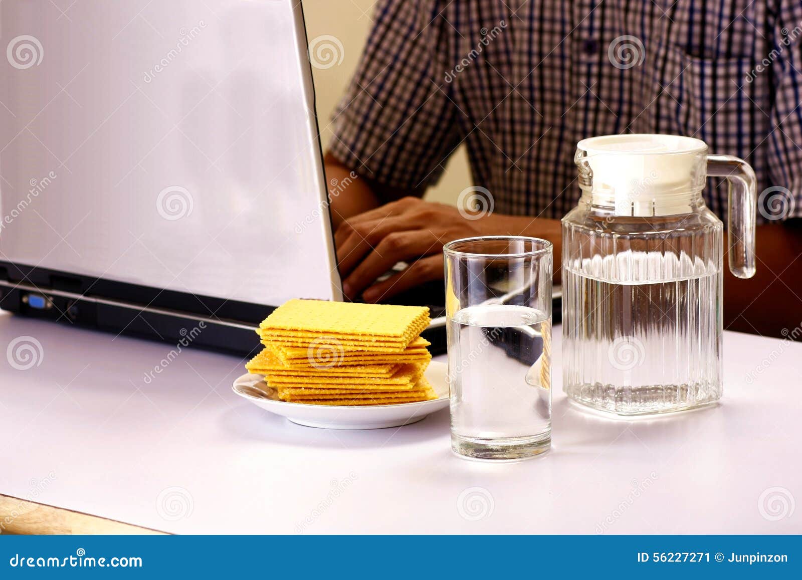 Glass and Pitcher of Water and a Stack of Crackers and Man Working on a ...