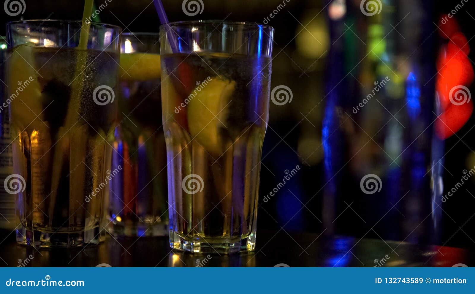Glasses With Alcoholic Cocktails Standing On Bar Counter At Nightclub