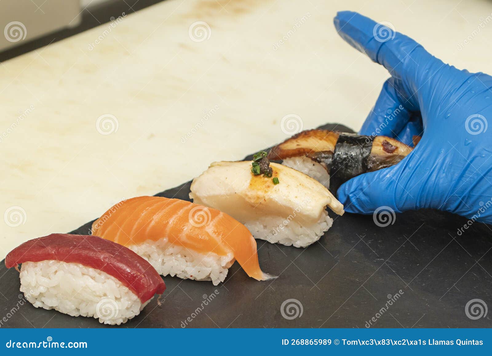 The Gloved Hands of a Chef Placing Freshly Made Nigiris on a Black ...