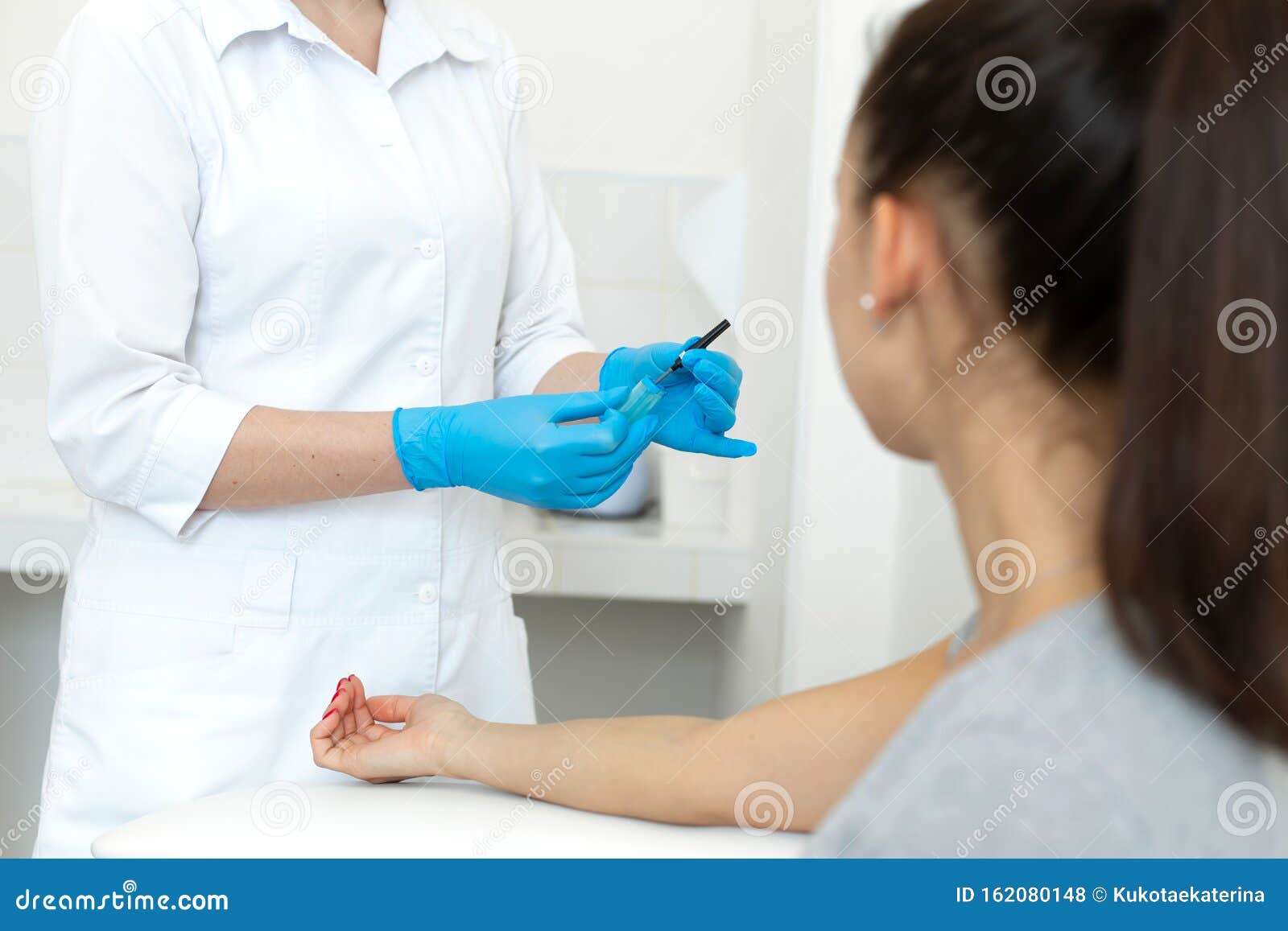 A Gloved Nurse Inserts A Needle Into A Vein On The Patients Arm And ...