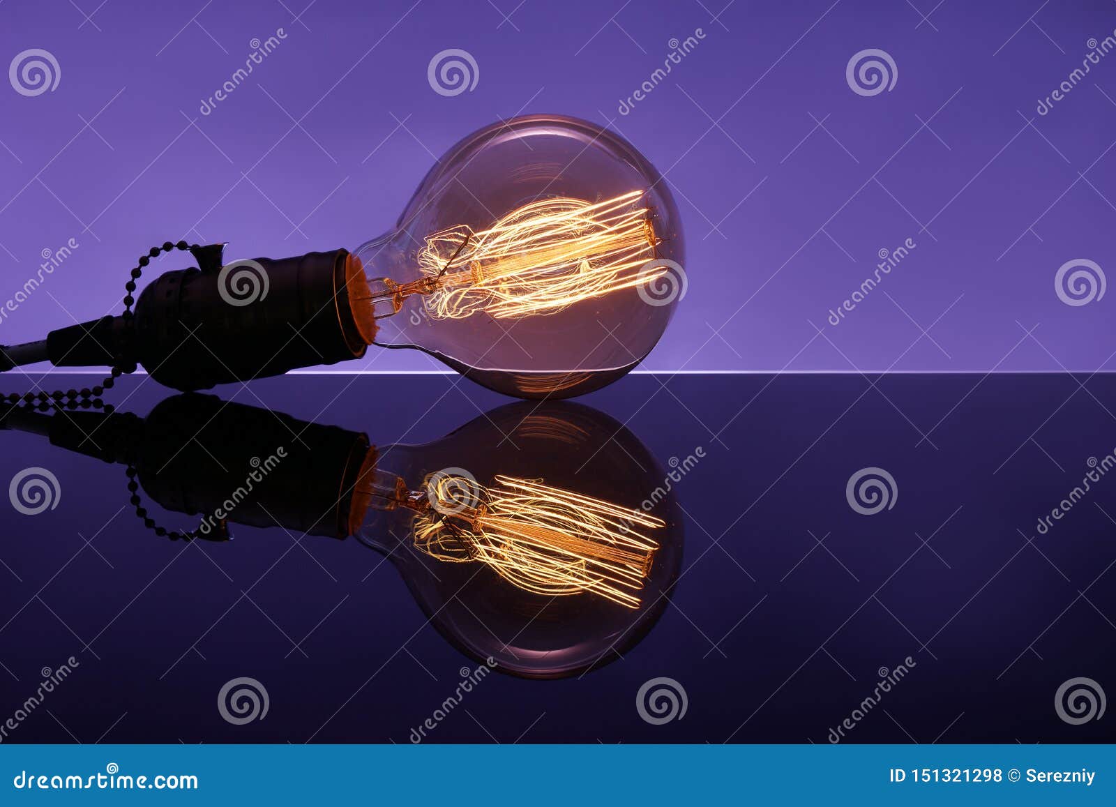 Glowing Retro Light Bulb with Reflection on Color Table Stock Photo ...