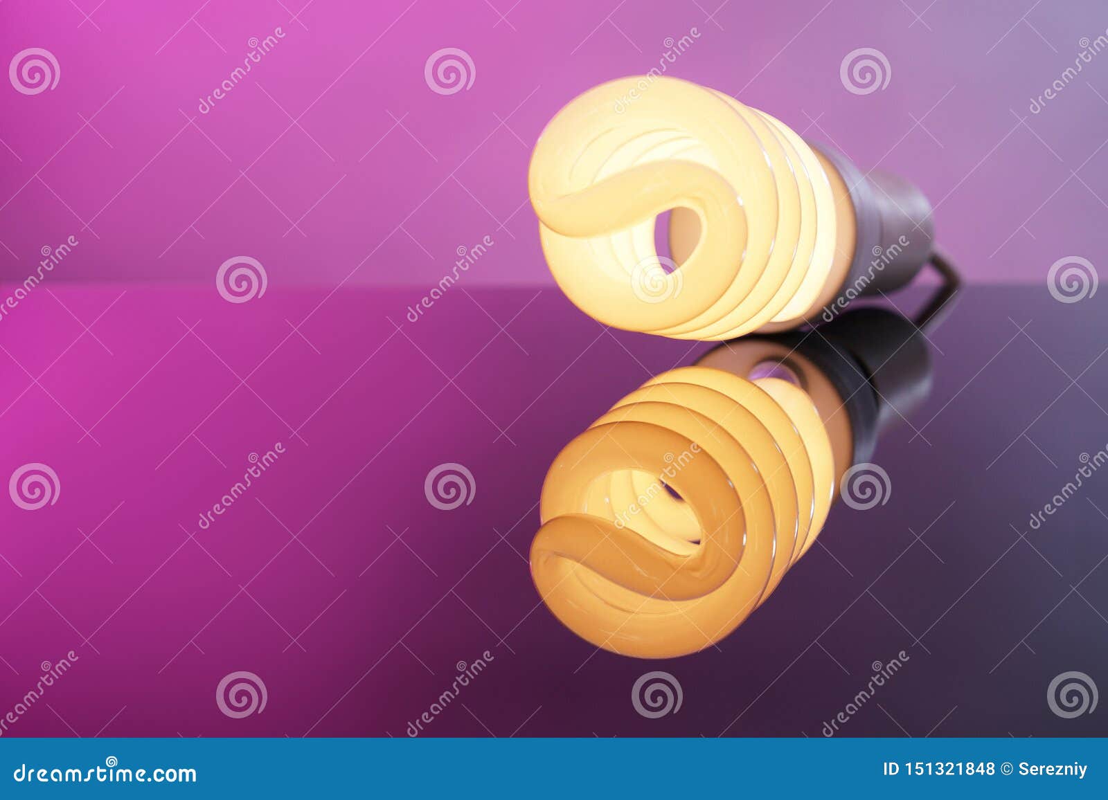 Glowing Spiral Light Bulb with Reflection on Color Table Stock Photo ...