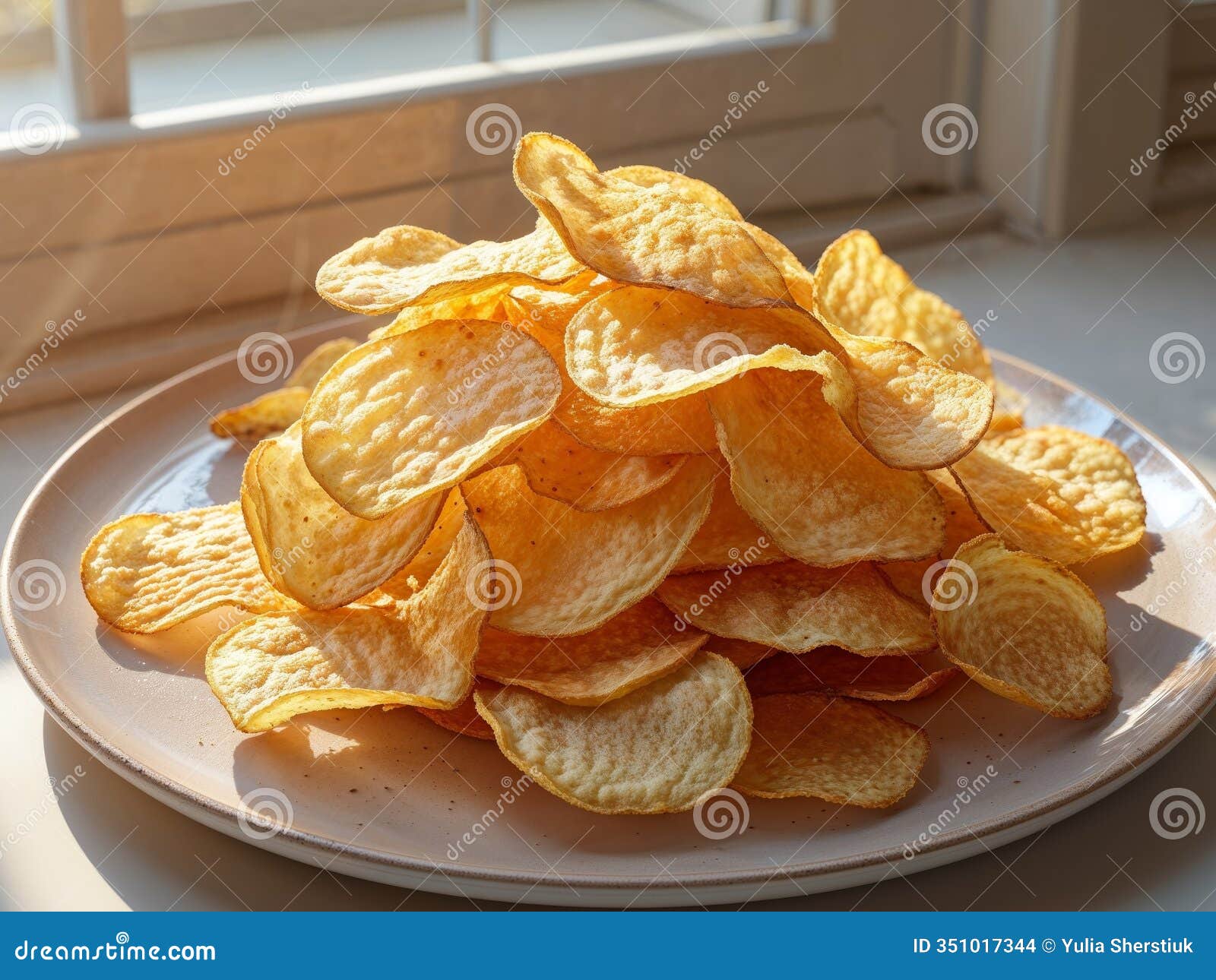 Golden Crispy Potato Chips on Plate with Sunlight in Background Stock ...