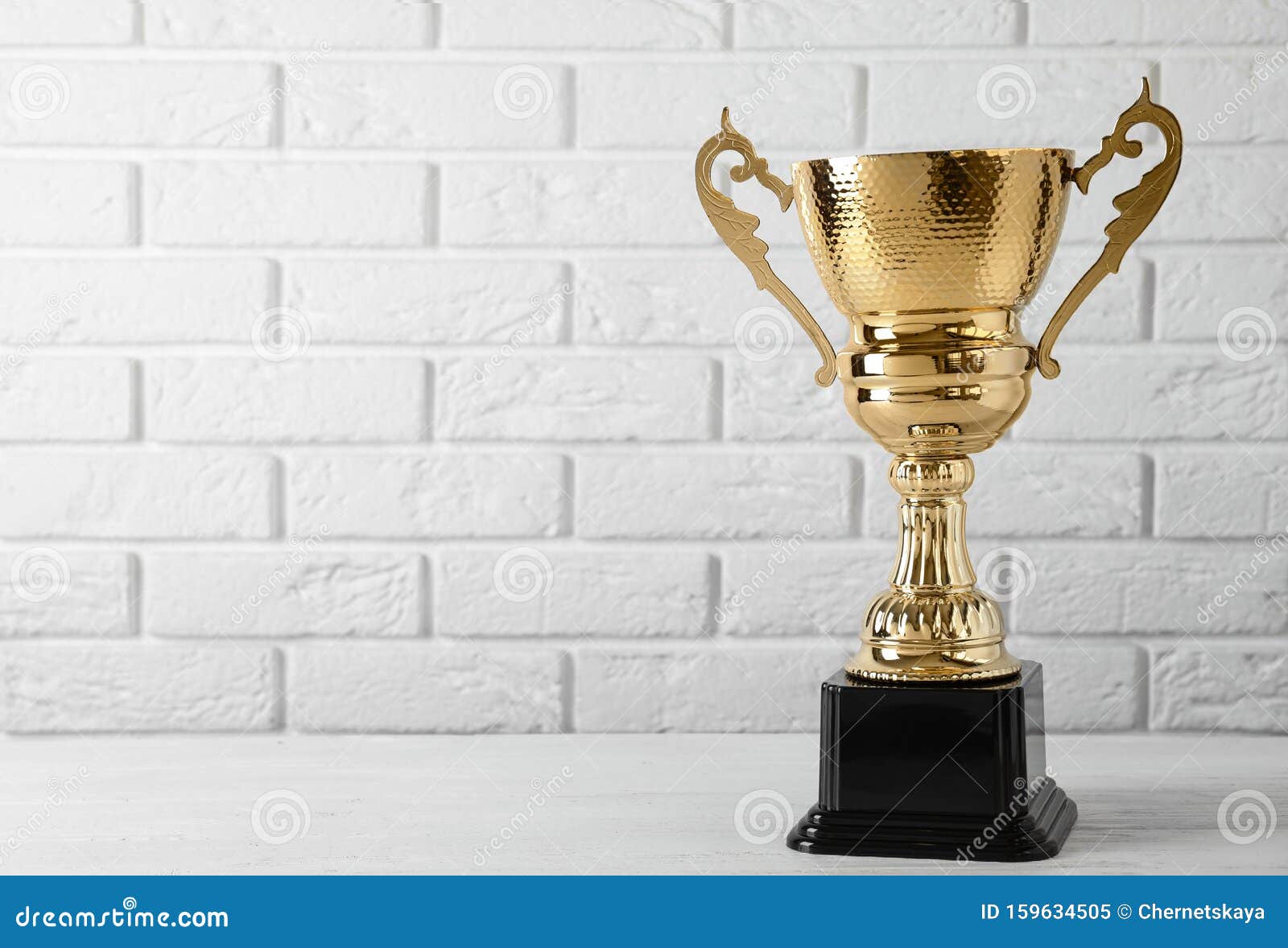 Golden Trophy Cup on Table Near Brick Wall. Space for Text Stock Image ...
