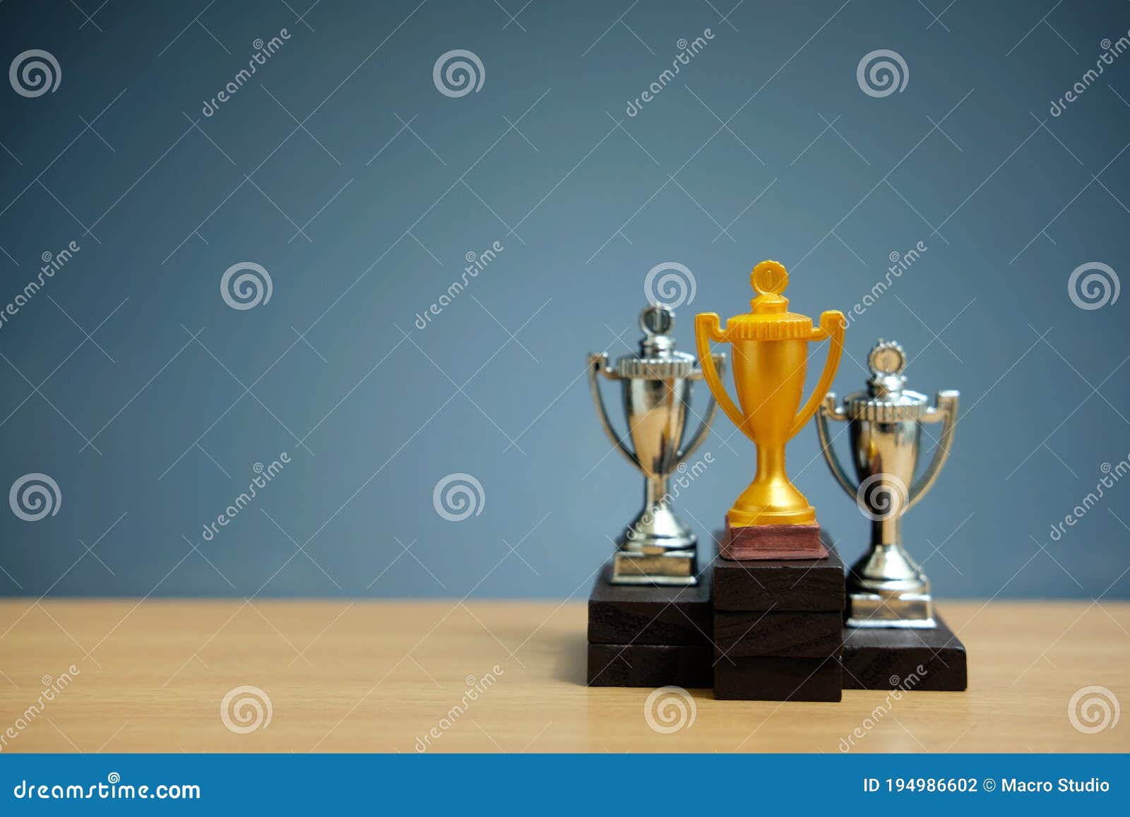 Golden Trophy with Two Silver Trophy at Back Stand on Black Podium ...