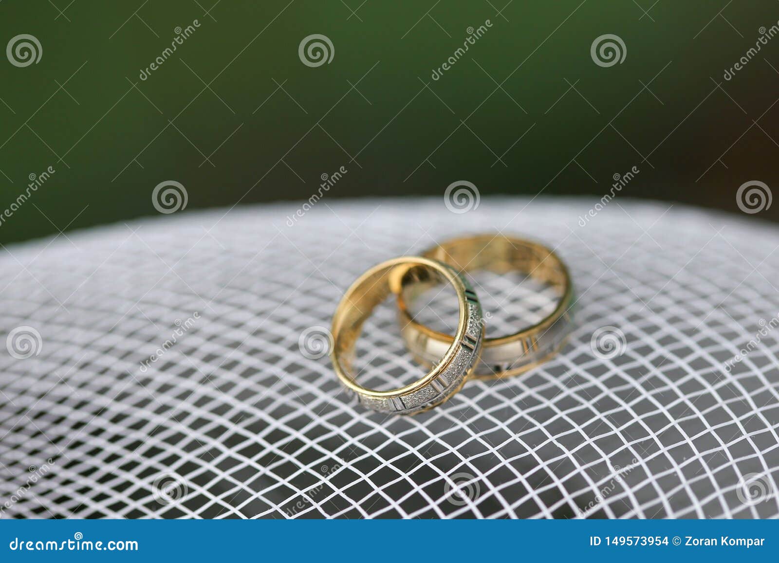 Golden Wedding Rings on the White Mesh with Green Background Stock ...