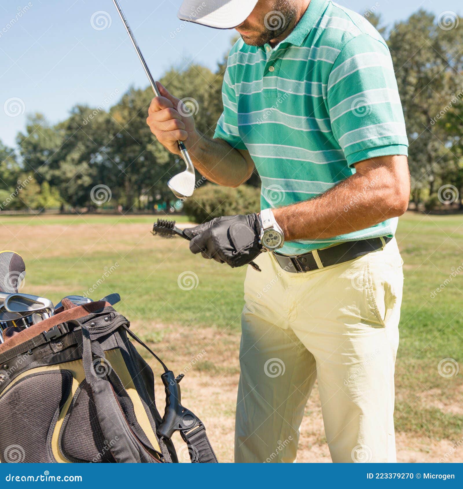 Golfer cleaning a club stock photo. Image of person - 223379270