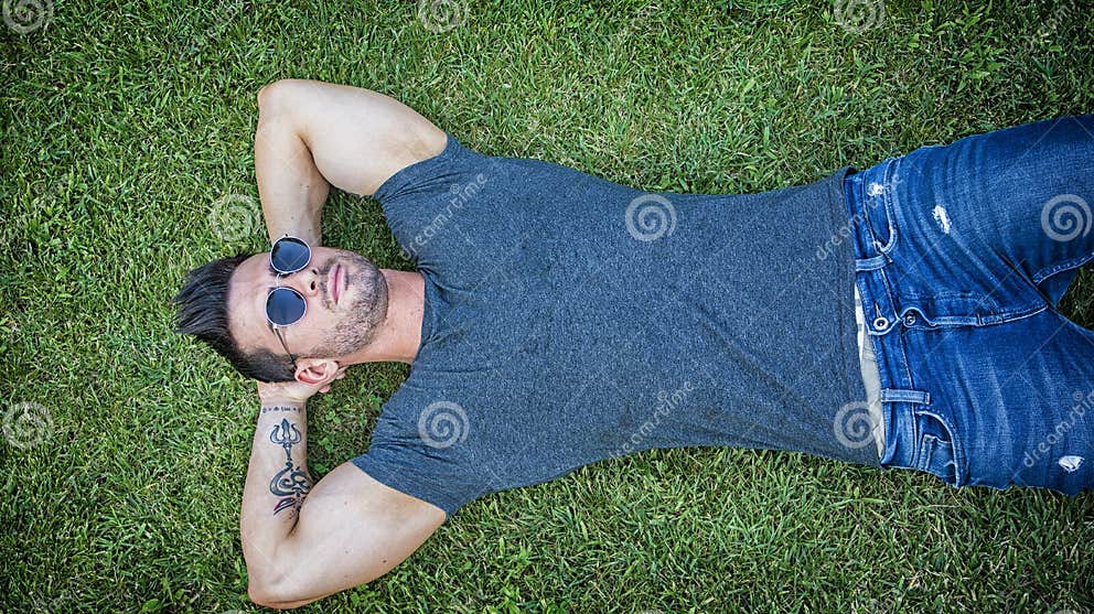 Good Looking Fit Male Model Relaxing Lying On The Grass Stock Image