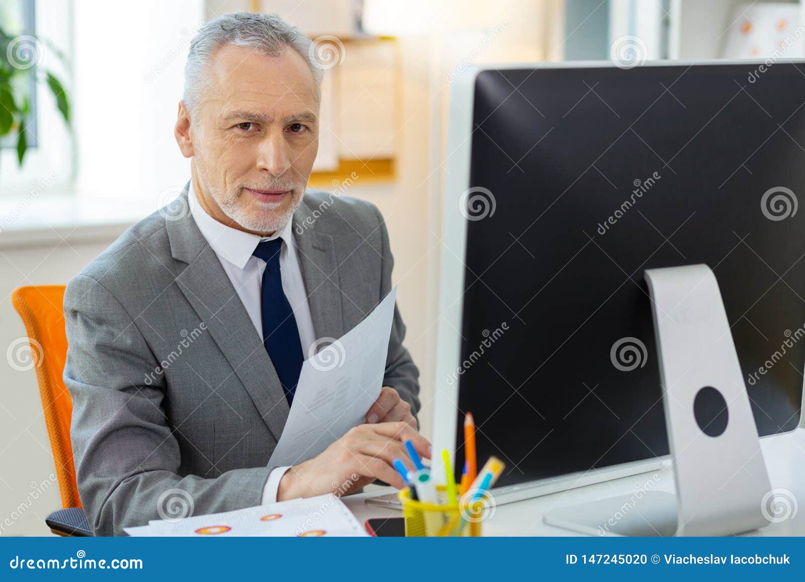 Good-looking Senior Office Worker Inspecting Papers and Computer ...