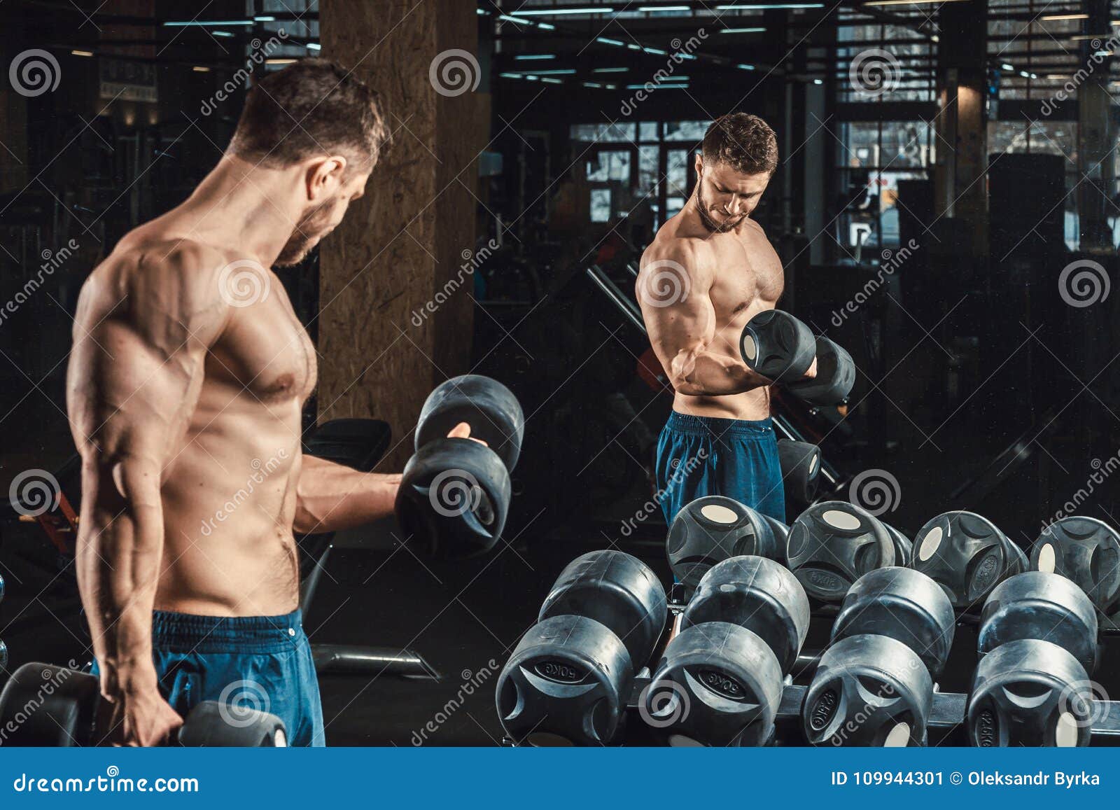 Good Looking Young Man Lifting Dumbbells and Working on His Biceps in ...