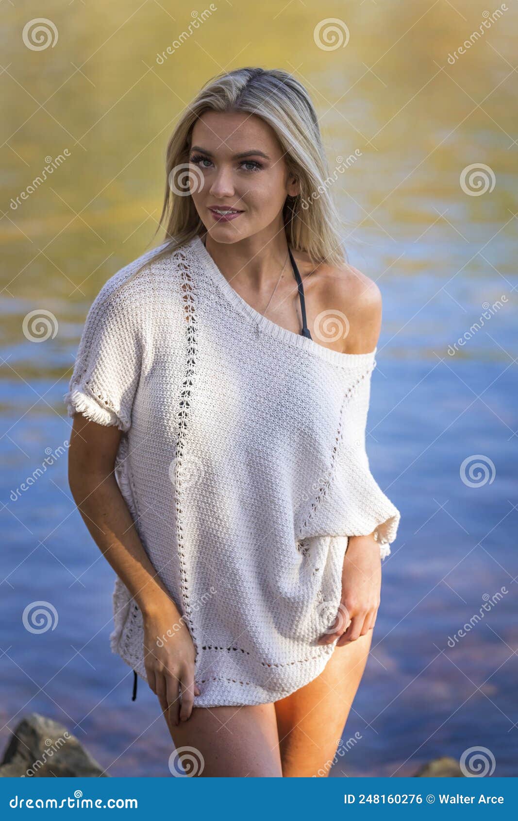 A Lovely Blonde Bikini Model Poses Outdoors Near A Lake While Enjoying The Summer Weather Stock
