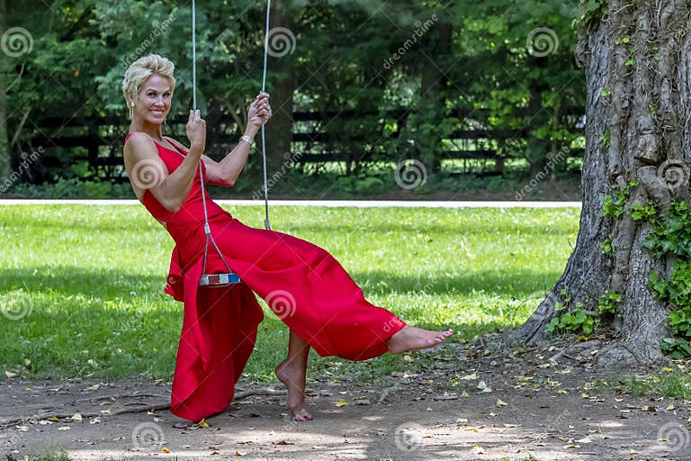 Gorgeous Blonde Model Posing Outdoors Wearing A Red Evening Gown Stock