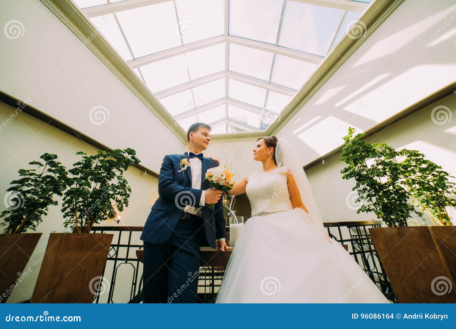 Gorgeous Bride and Elegant Groom Posing in Modern Background. View from ...