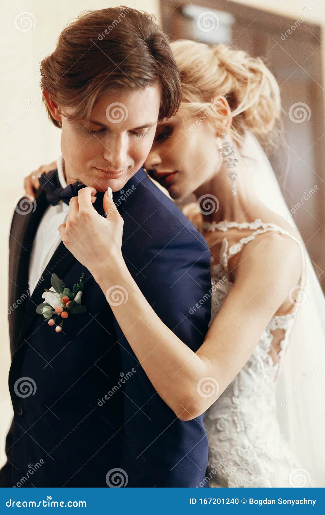 Gorgeous Bride In Wedding Dress Hugging Handsome Groom From Behind In