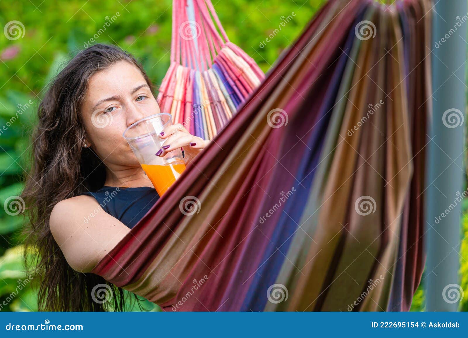 Gorgeous Girl Lying On The Hammock Relaxing And Drinking Orange Juice