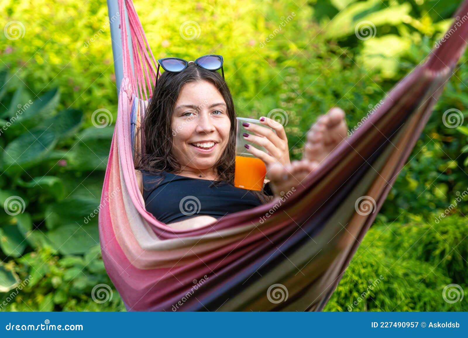 Gorgeous Girl Lying On The Hammock Relaxing And Drinking Orange Juice