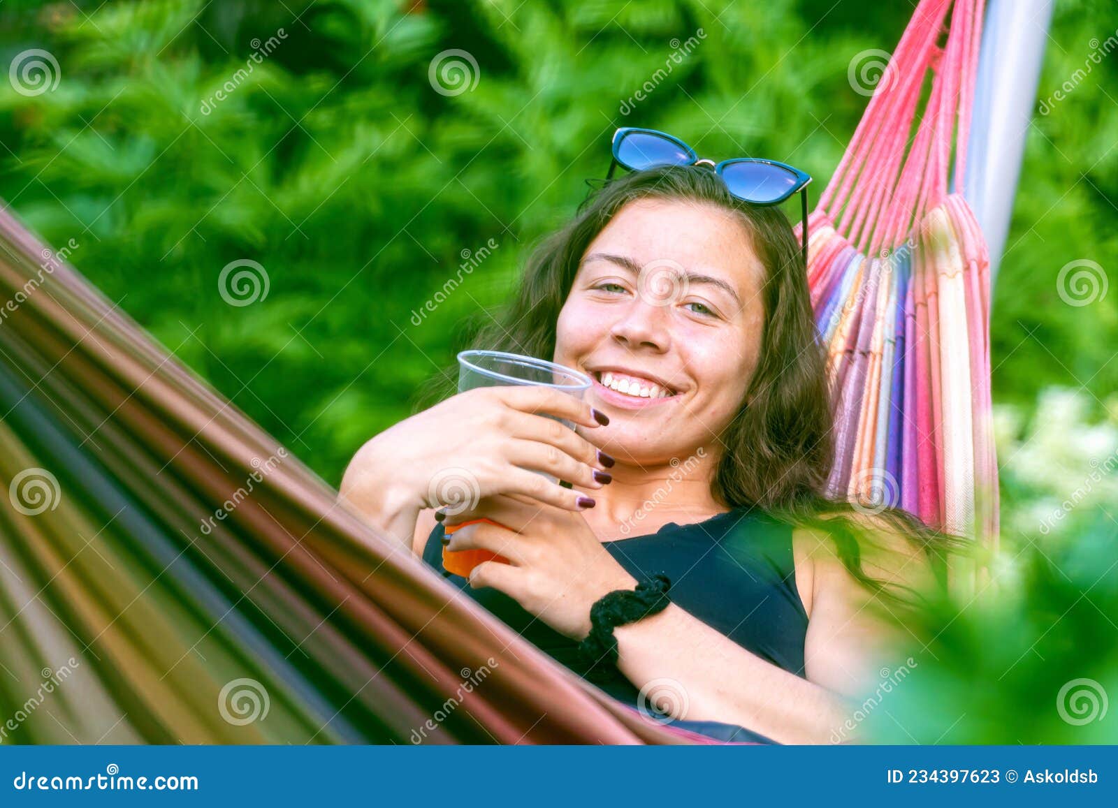 Gorgeous Girl Lying On The Hammock Relaxing And Drinking Orange Juice