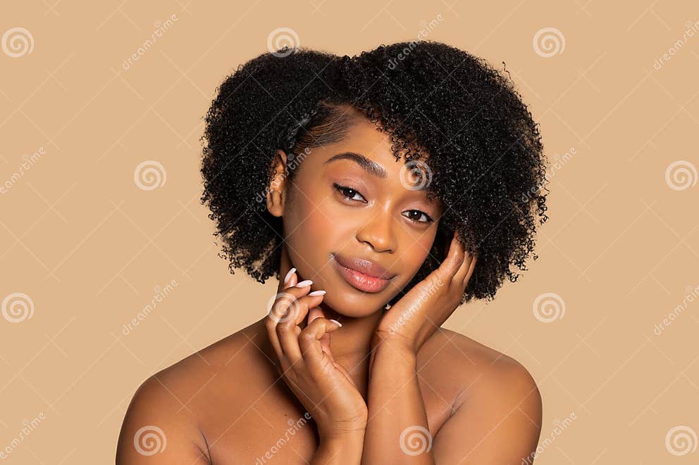 Graceful Black Woman With Curly Hair Touches Face Beige Tone Stock