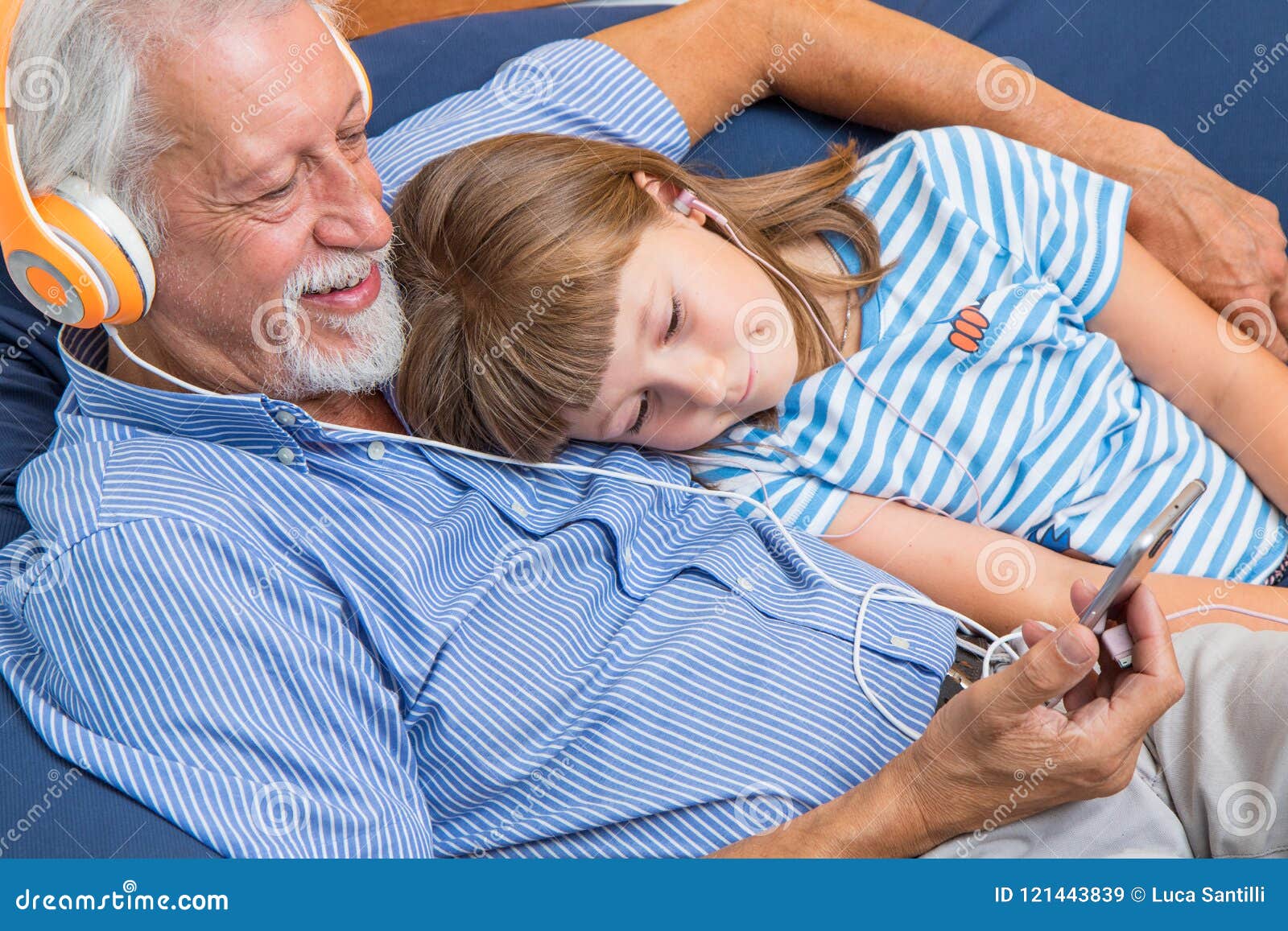 Grandfather And Grandson With Headphones Listen To Music Hugging Stock