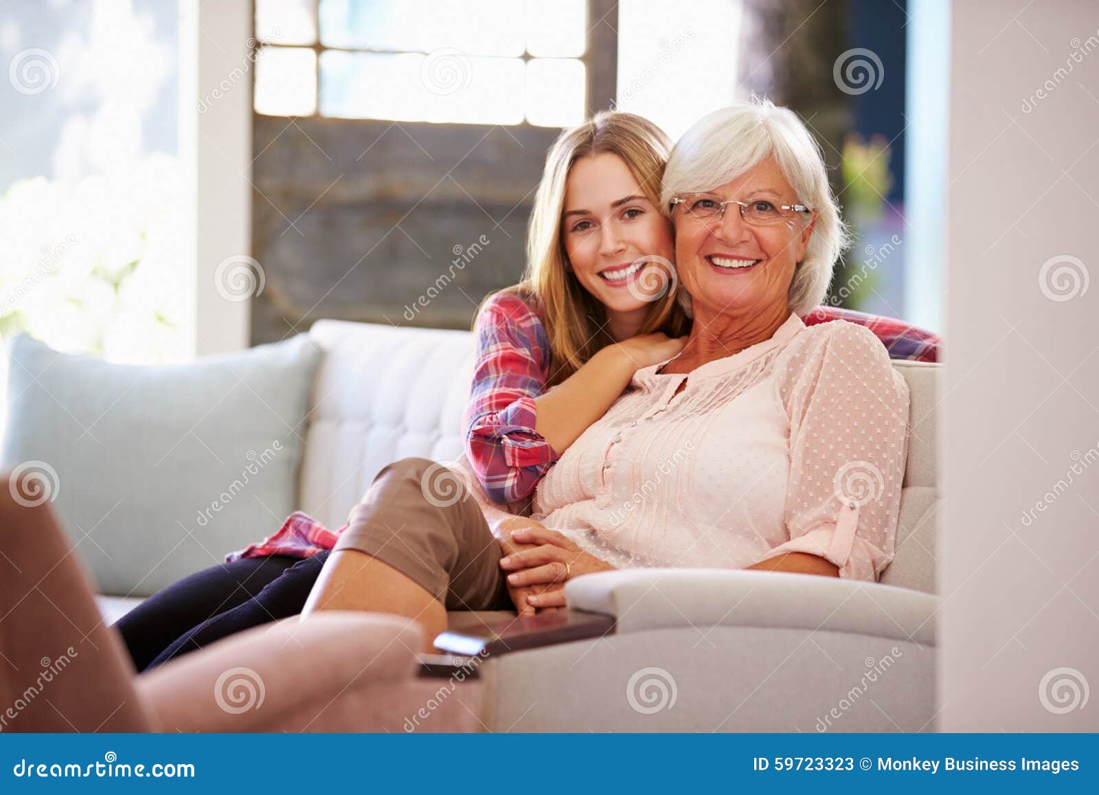 Grandmother With Adult Granddaughter Relaxing On Sofa Stock Image