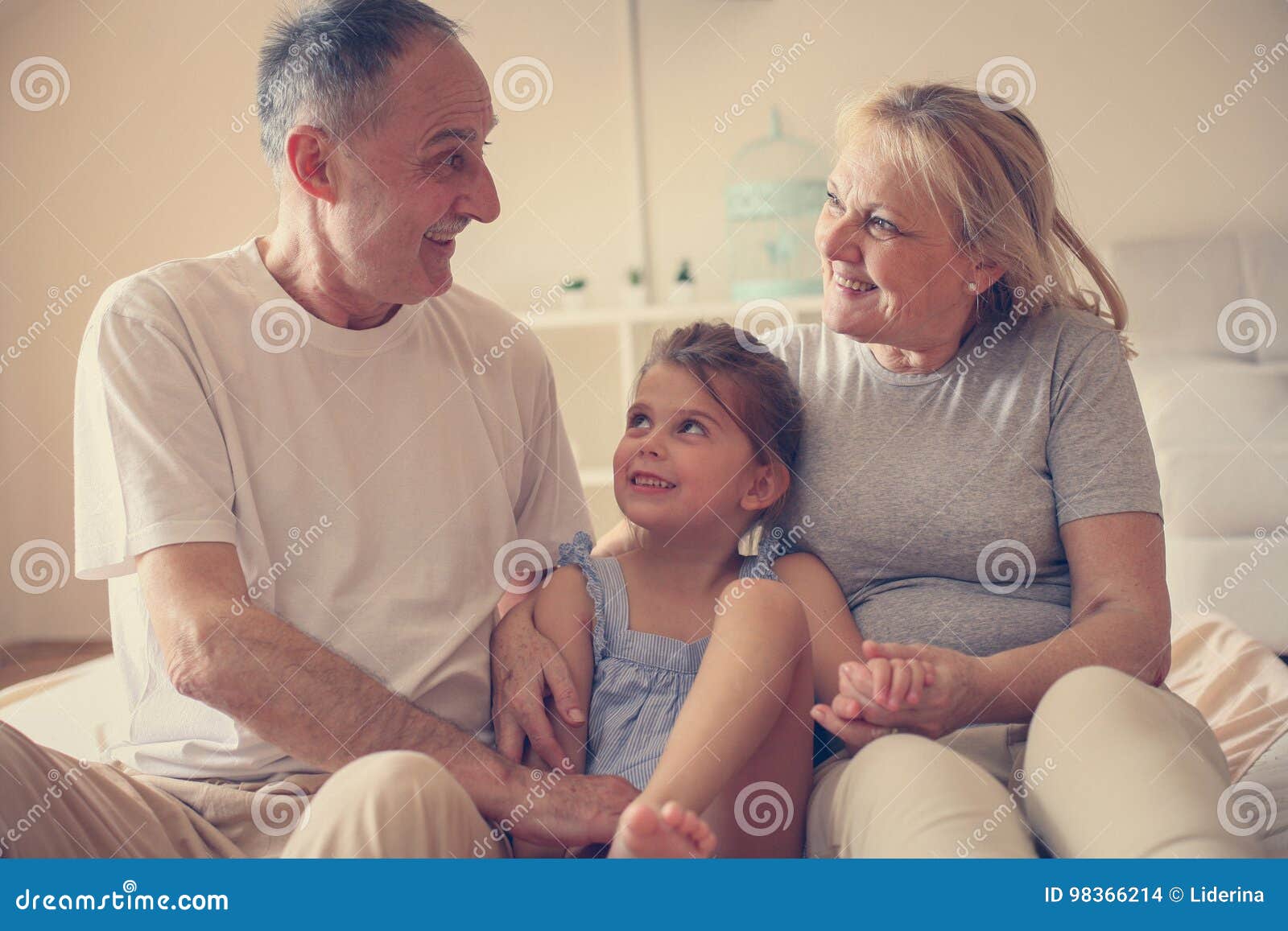 Grandmother And Grandfather Sitting On Bed Together With Their