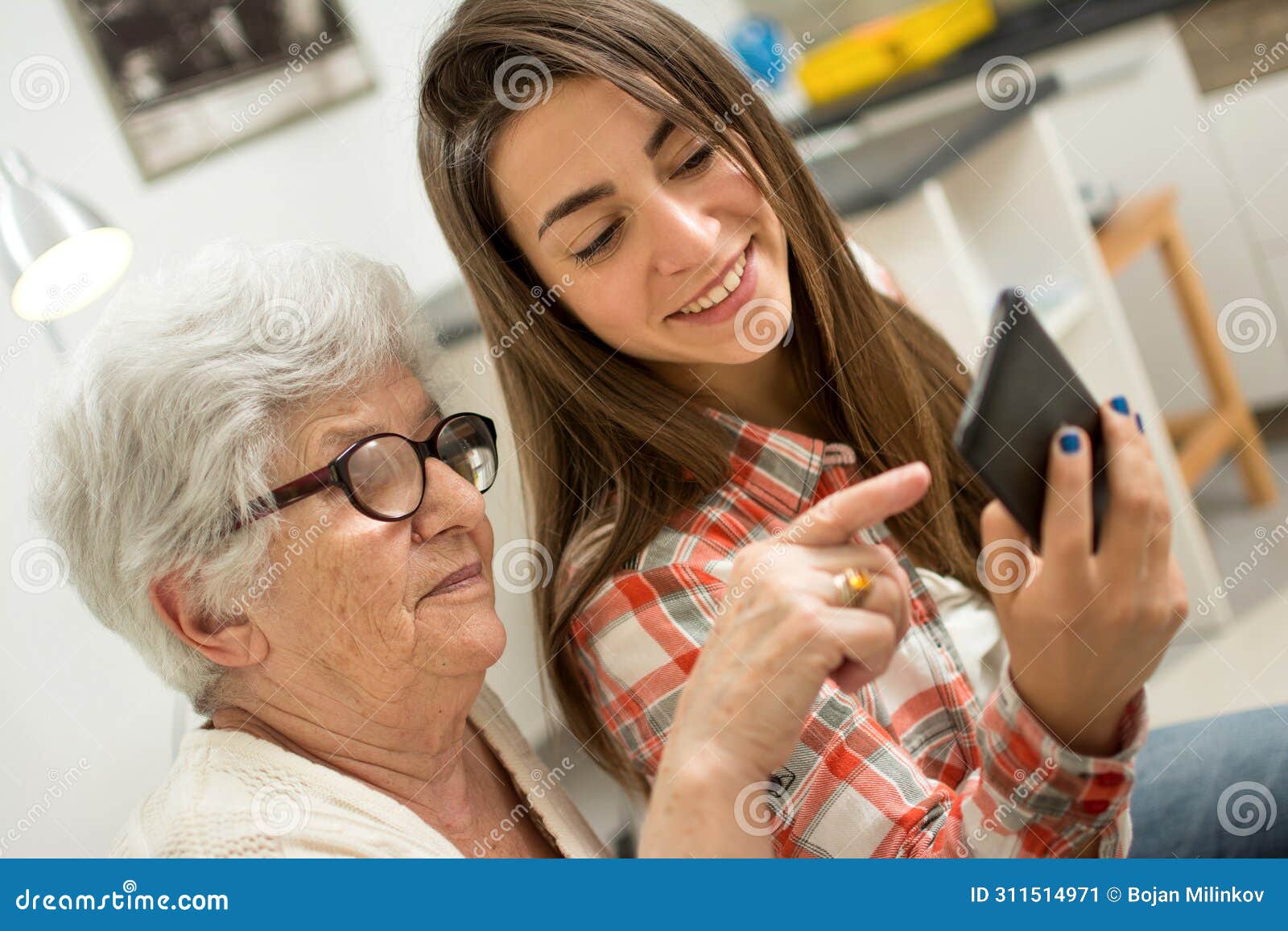 Grandmother Showing Something On Mobile Phone To Her Young