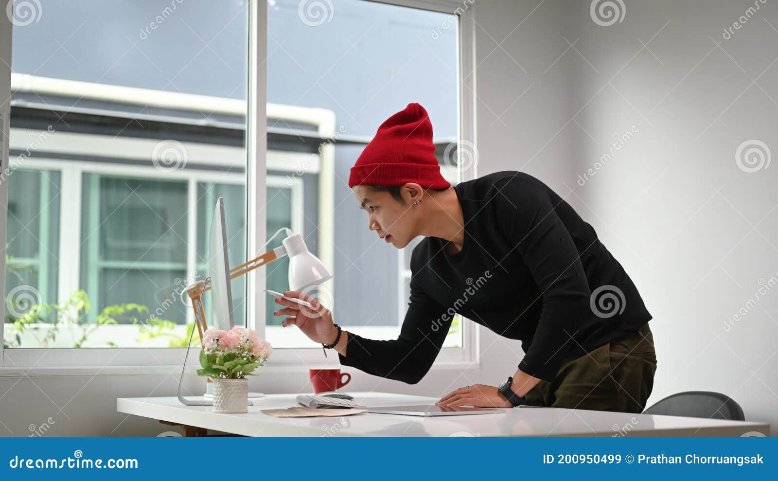 A Graphic Designer Man in Red Wool Hat Standing at Table with Computer ...