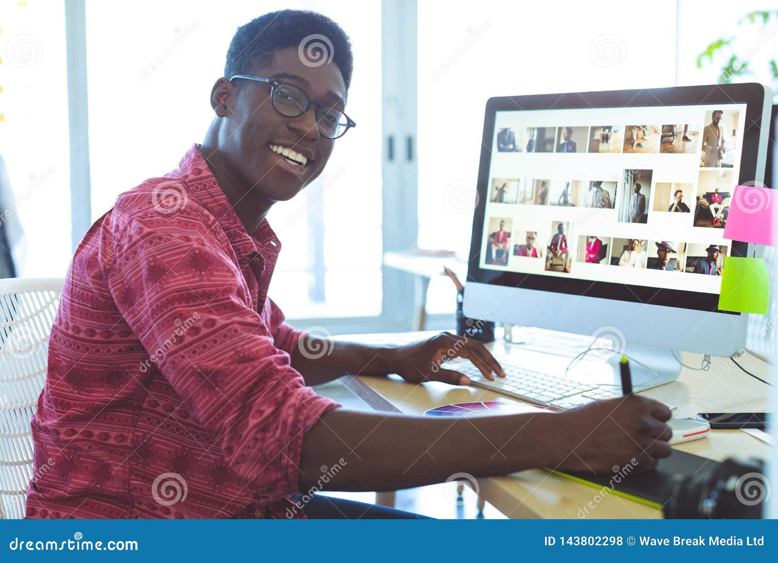 Graphic Designer Working On Graphic Tablet At Desk In Office Stock