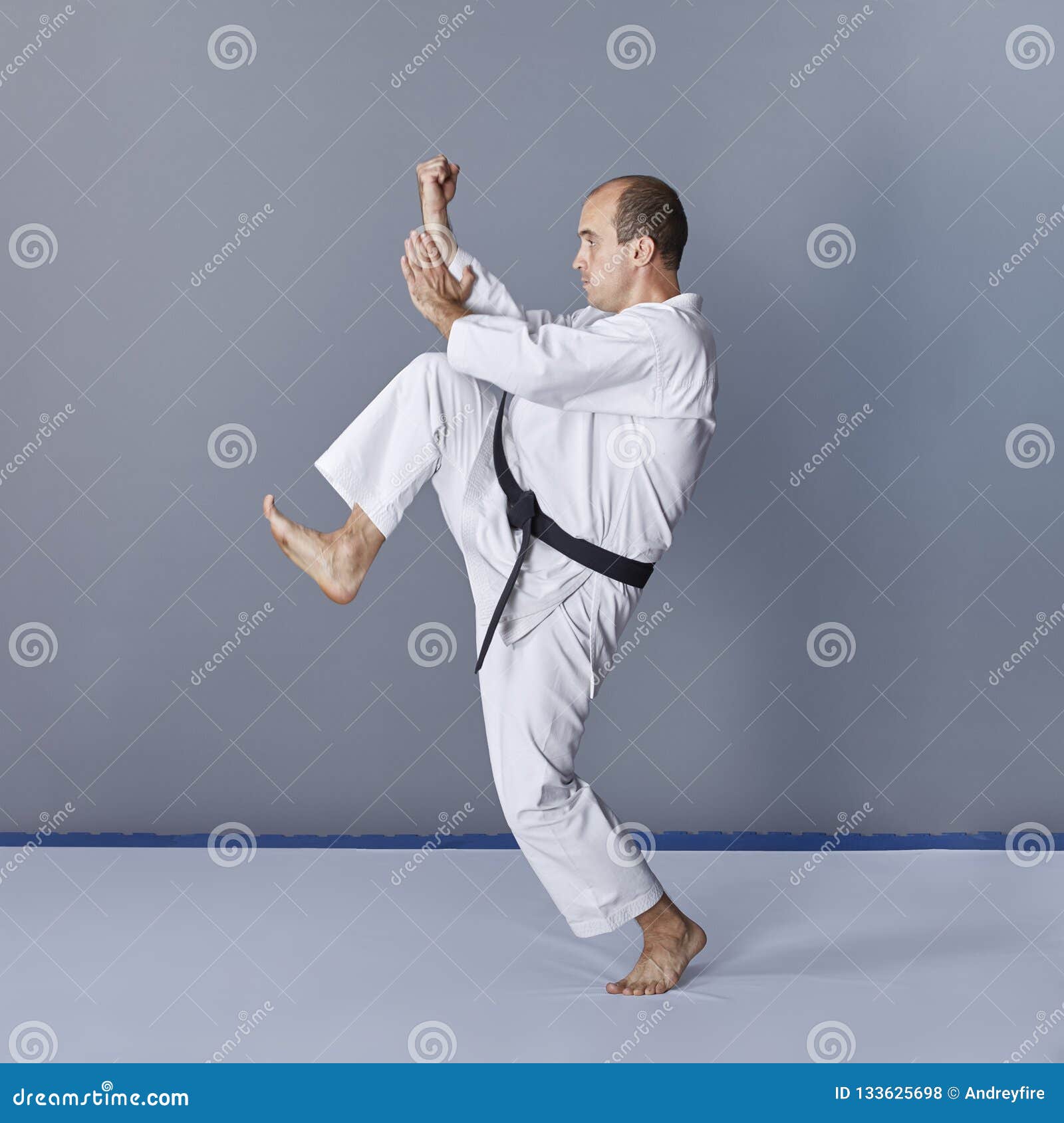 On a Gray Background, a Young Active Athlete Performs Formal Karate ...