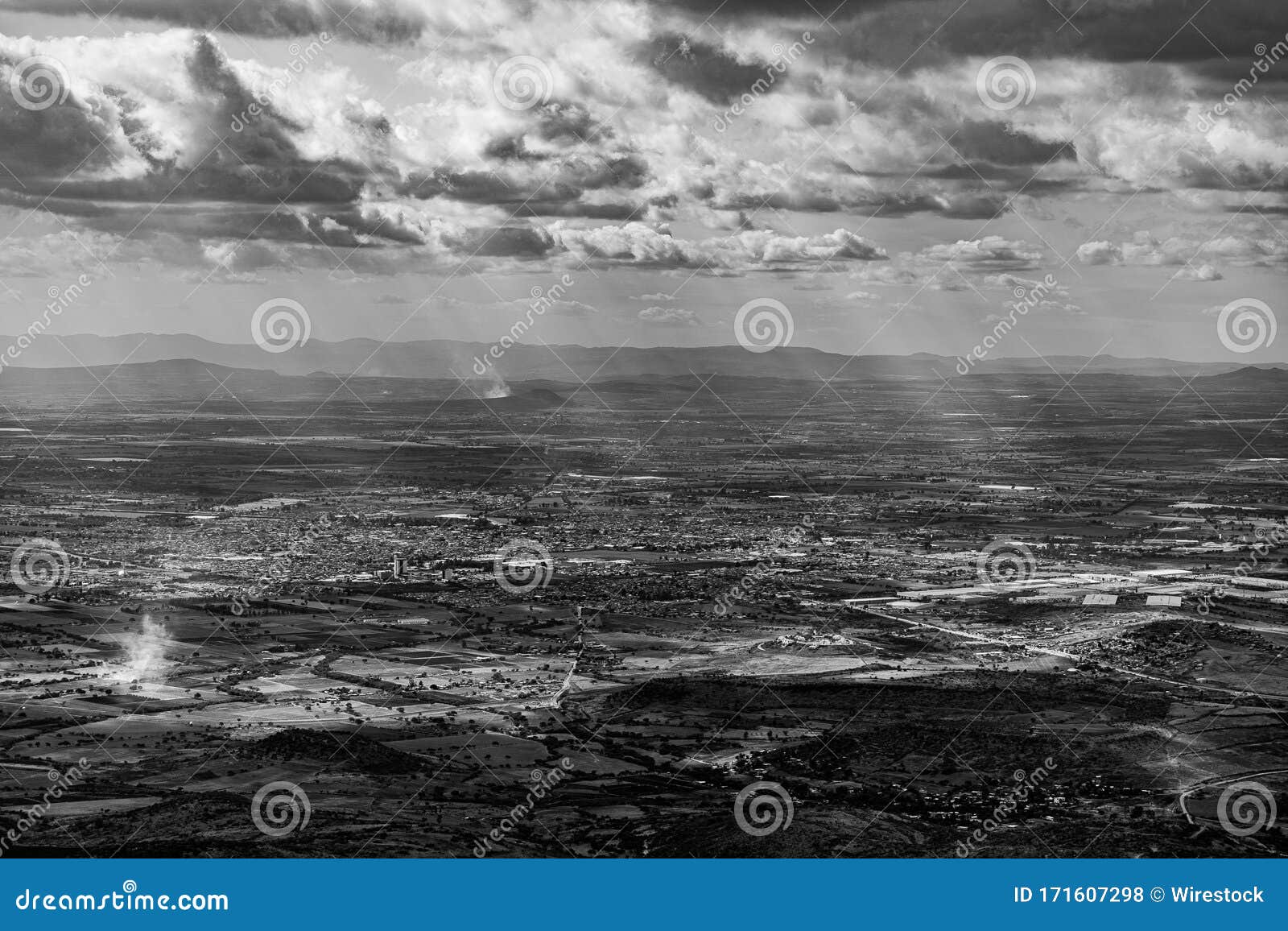 Grayscale Shot of Buildings with the Sun Shining Behind the Clouds ...