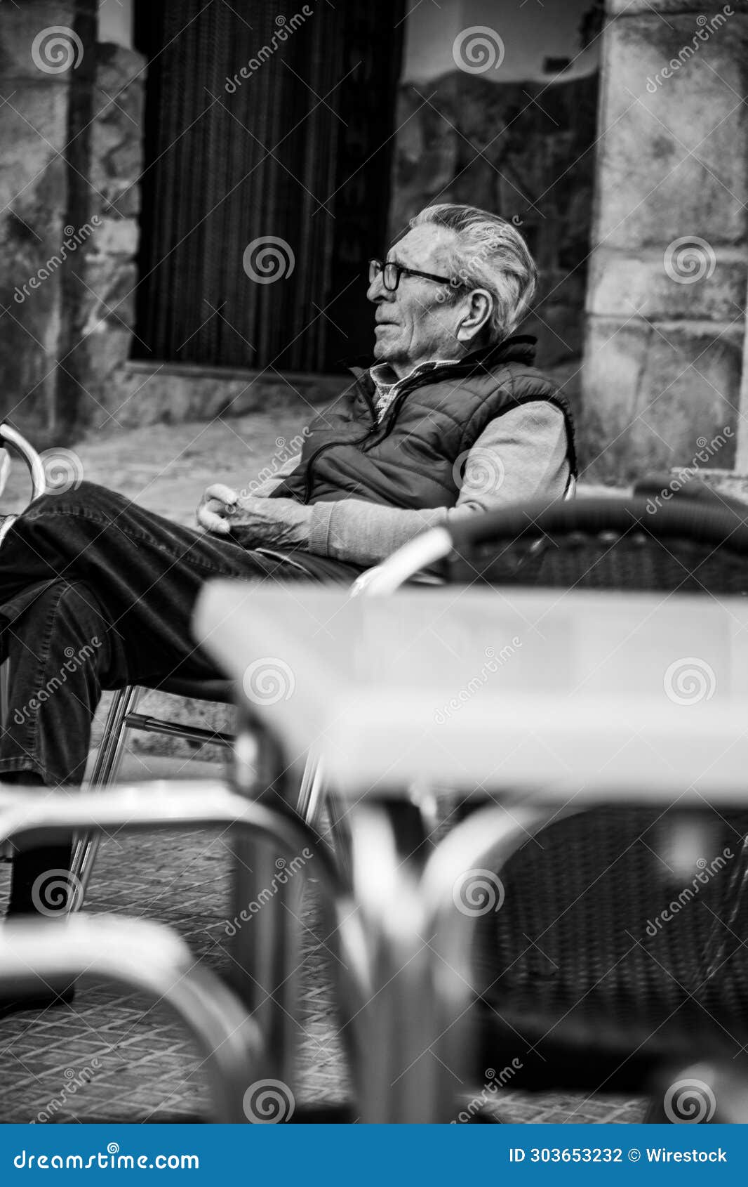Grayscale Shot of an Elderly Person Resting on the Terrace of the Bar ...