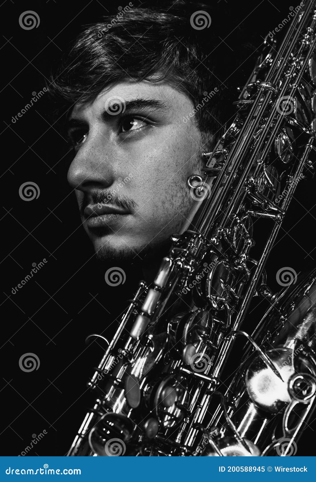 Grayscale Shot of a Handsome Guy Holding His Saxophone on a Dark ...