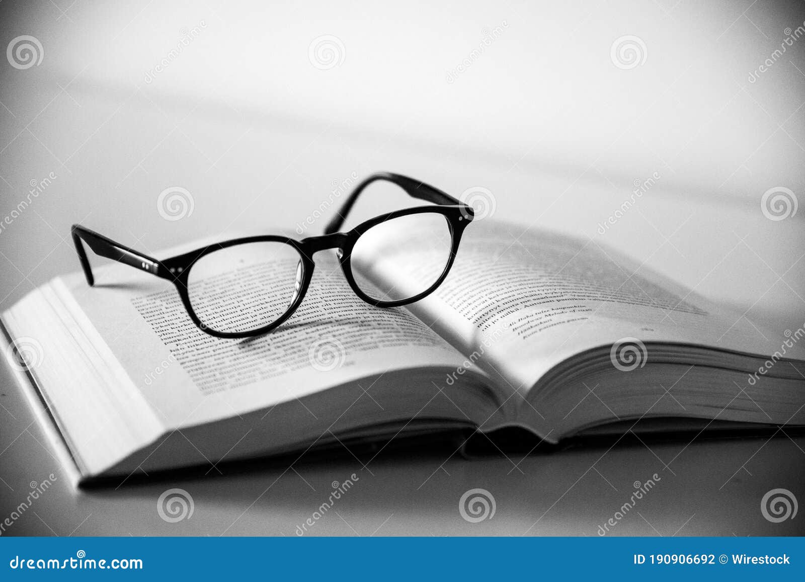 Grayscale Shot of a Pair of Glasses on an Open Book with a White ...