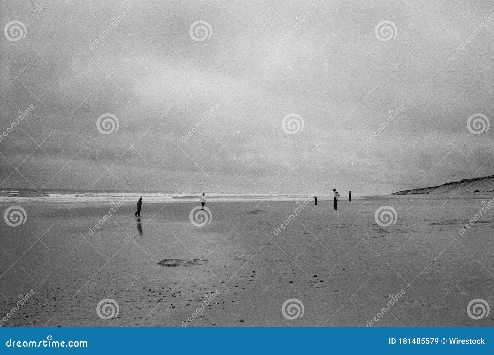 Grayscale Shot of People Walking on a Beach Under a Cloudy Sky Stock ...