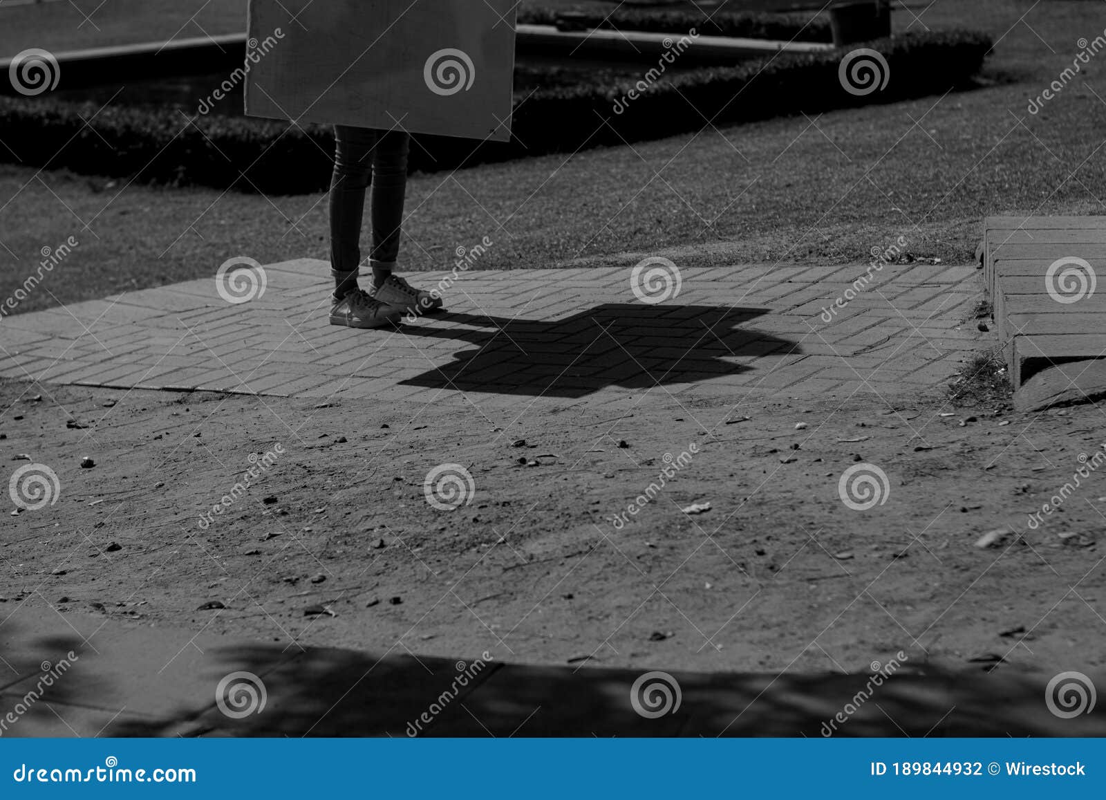 Grayscale Shot of Someone Standing Alone and Holding a Sign Outdoors ...
