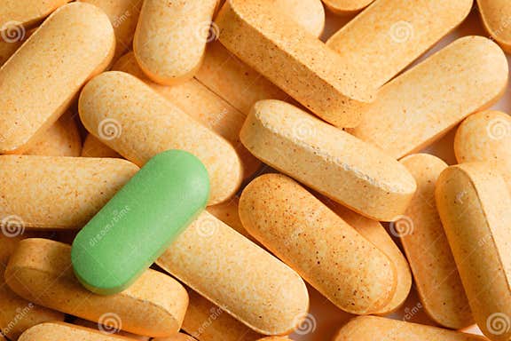 A Green Caplet among Orange Caps Stock Image - Image of medication ...