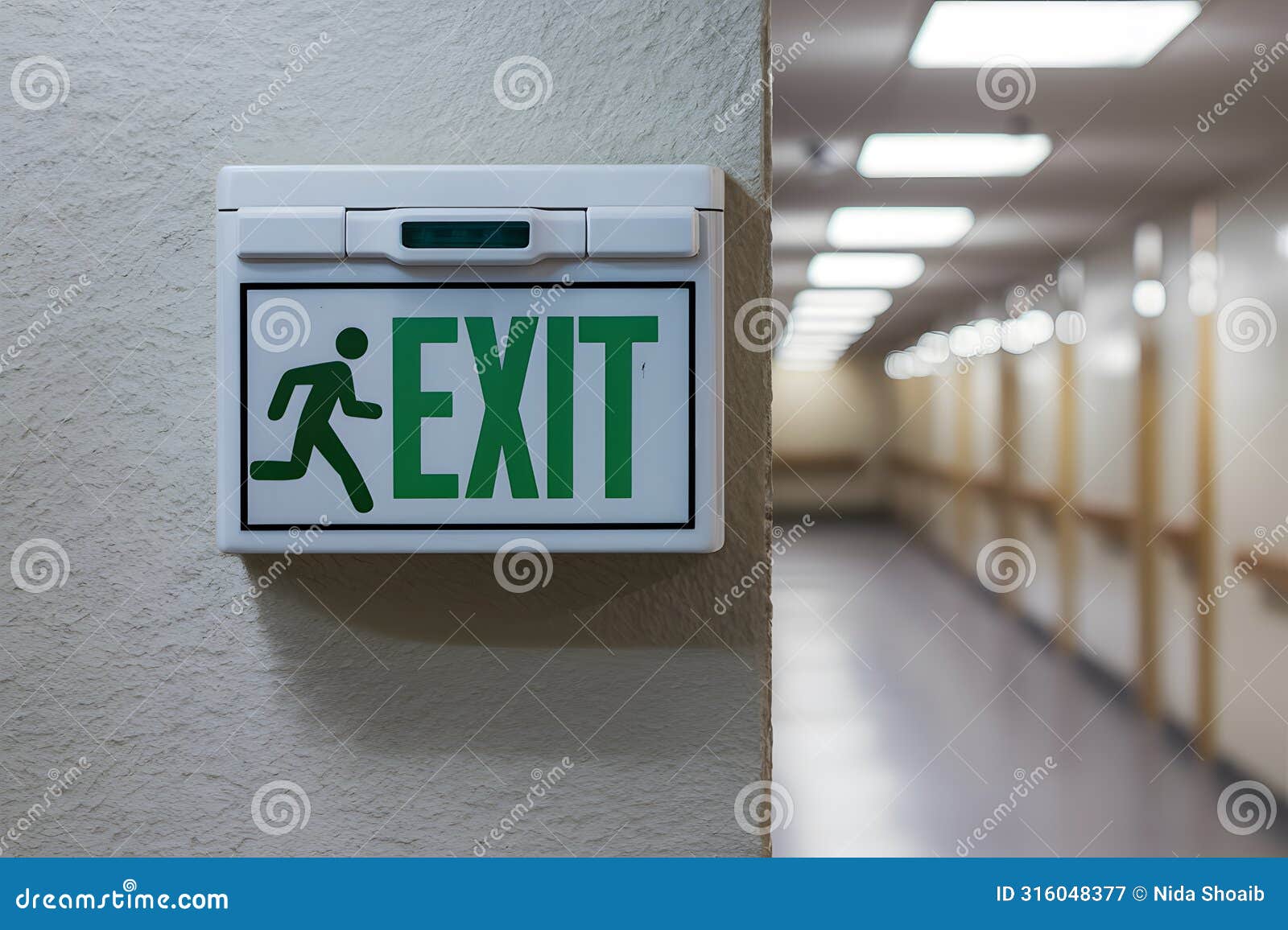 Green EXIT Sign on Light Wall, Blurred Corridor in Background, Running ...