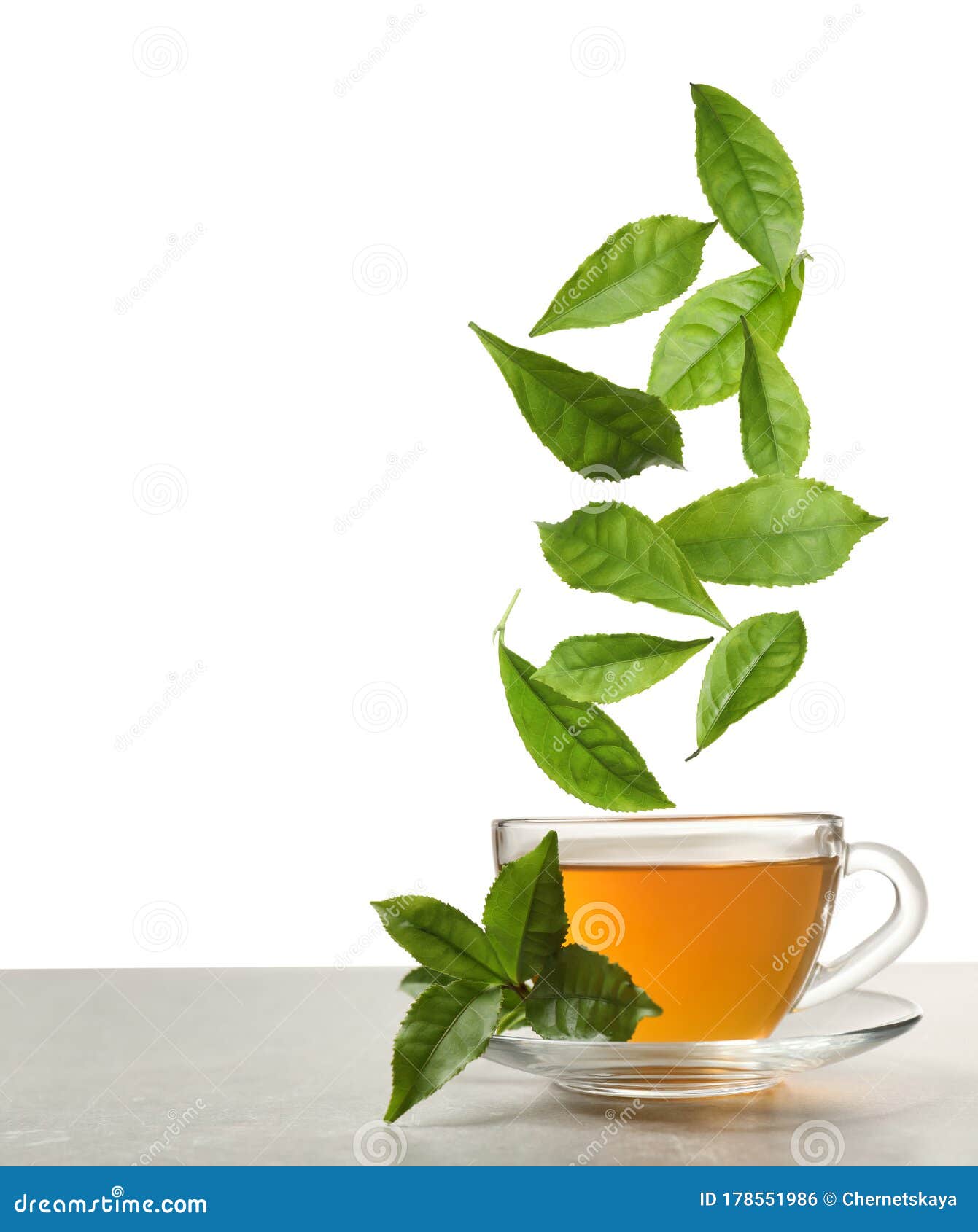 Green Leaves Falling into Cup of Tea on Table Against Background Stock ...