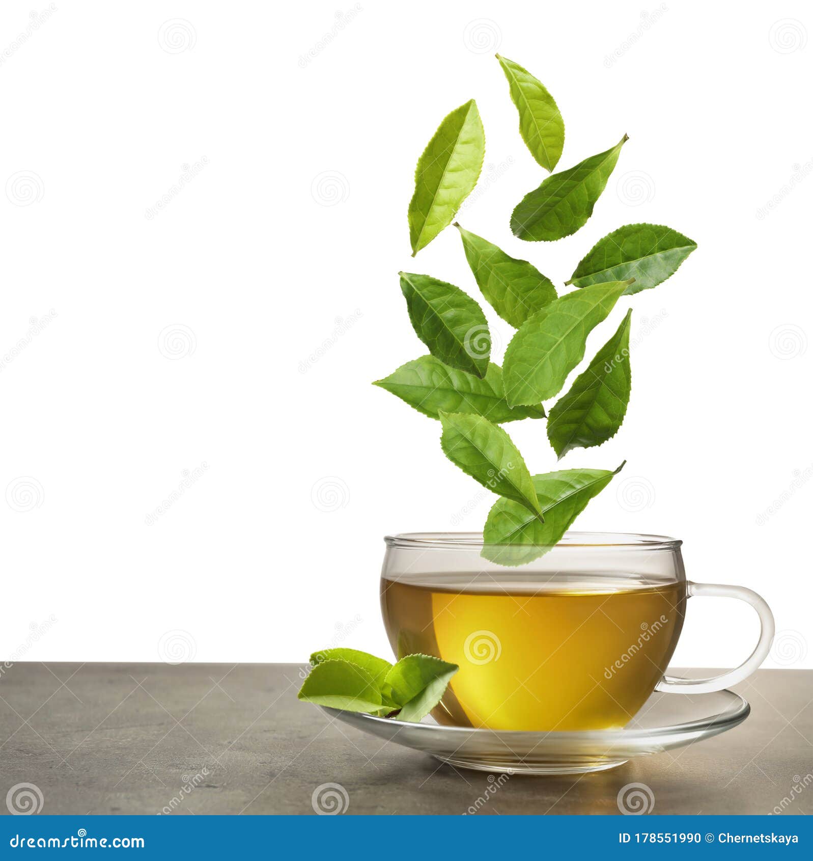 Green Leaves Falling into Cup of Tea on Table Against Background Stock ...