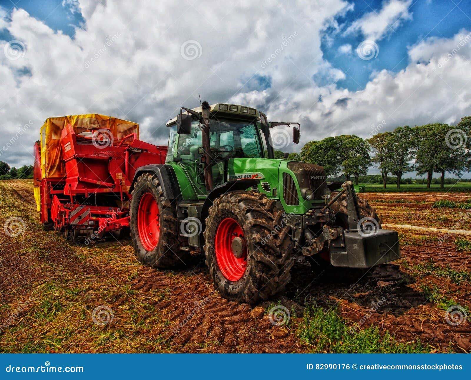 Green Tractor Pulling Red Bin On Field At Daytime Picture. Image: 82990176