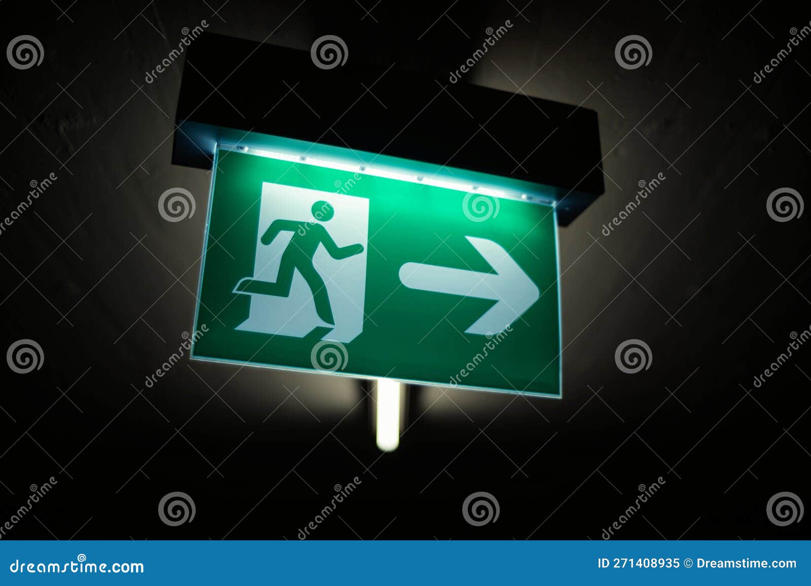 Green Wall Mounted Illuminated Exit Sign in a Dark Underground Parking ...