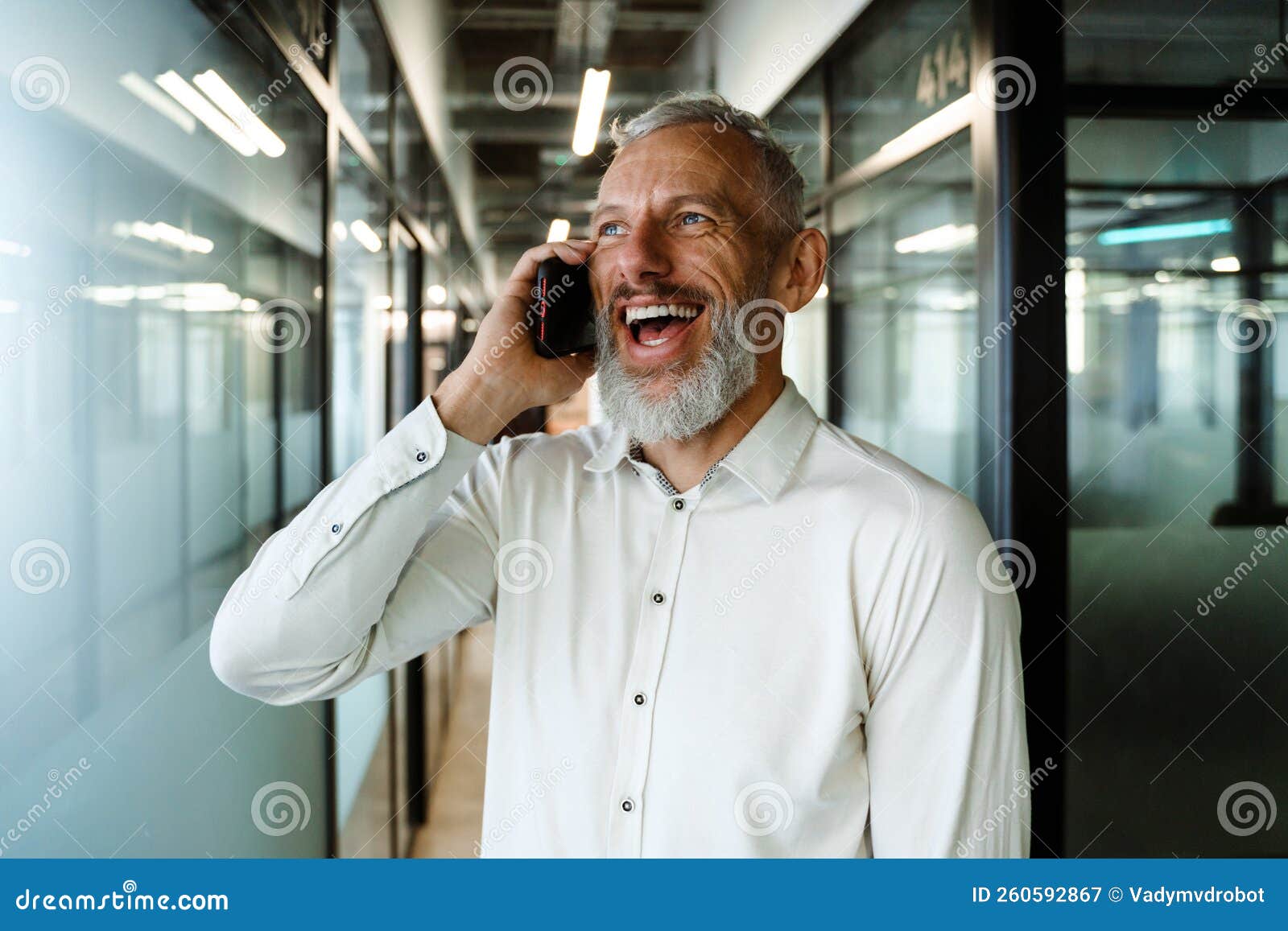 Grey Man Laughing and Talking on Cellphone while Working in Office ...