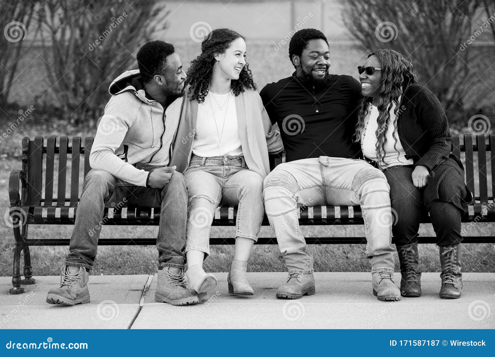 Grey Scale Shot of a Group of Friends Happily Sitting on a Bench Stock ...